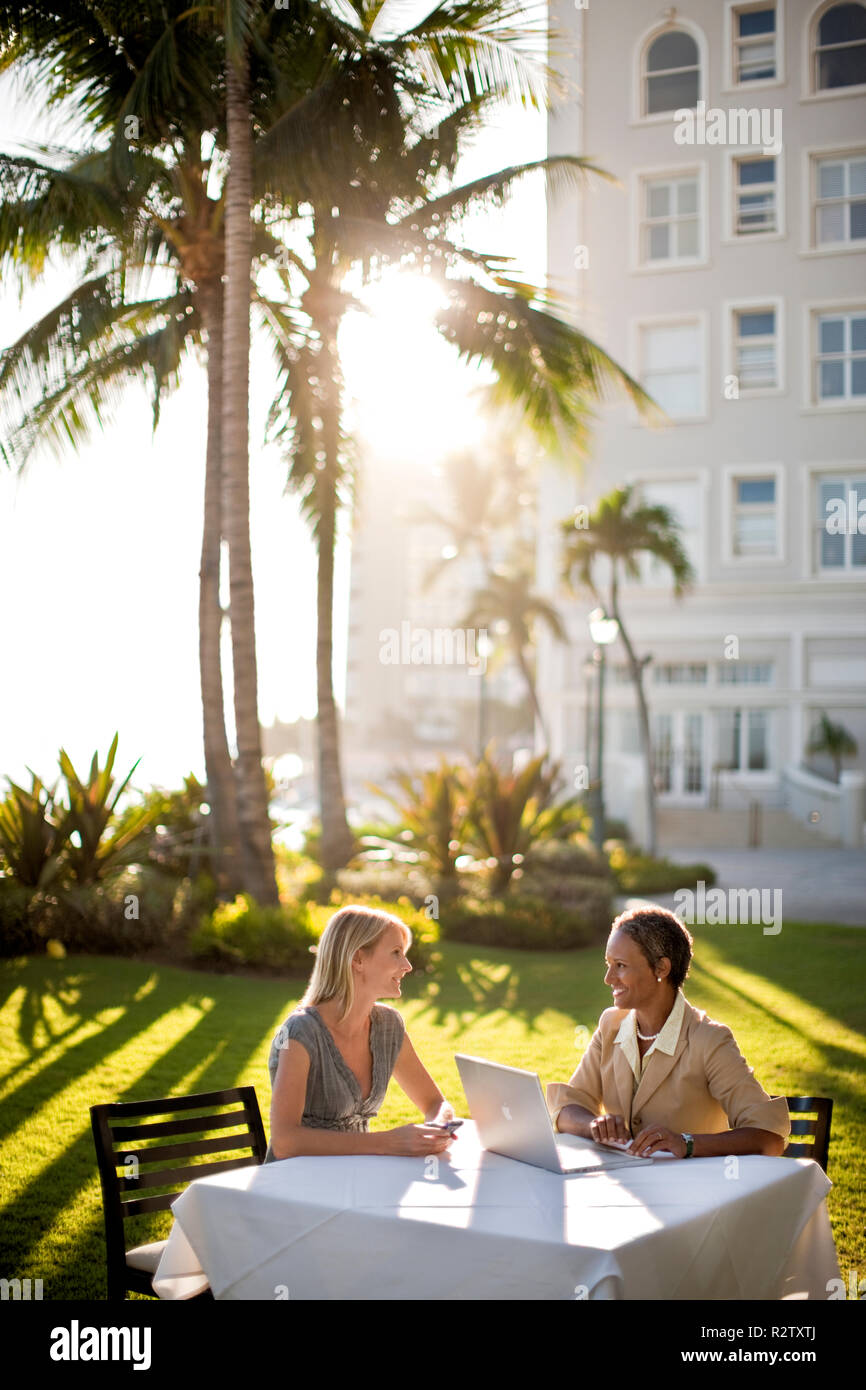 Two business colleagues sitting at outside table on lawn, for meeting ...