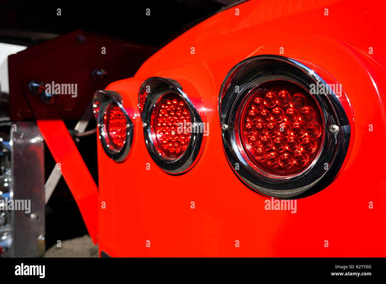 Line of rear round red marker lights with chrome rims on fender of red ...