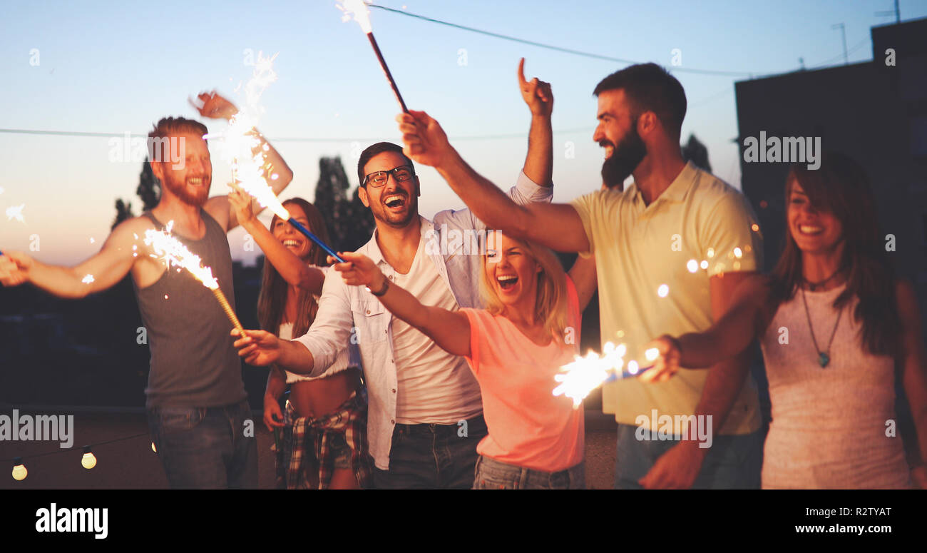 Friends enjoying a rooftop party and dancing with sparklers Stock Photo ...