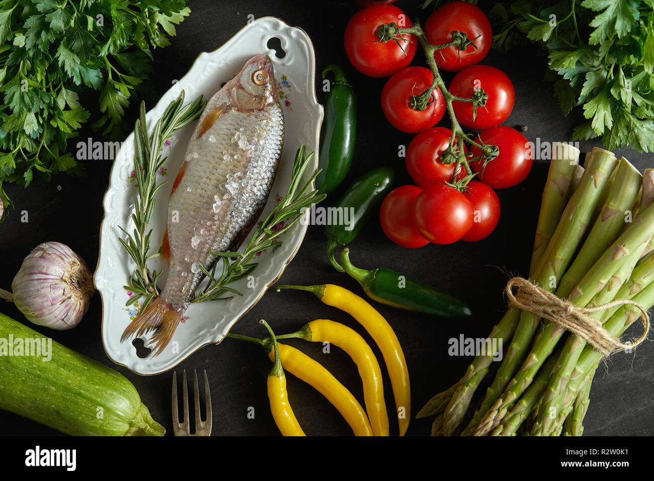 top view of one fresh raw dorada fish in a white dish with a set of ...