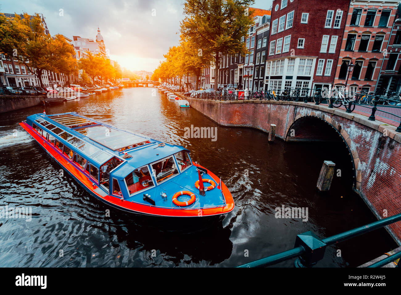 Tour boat at famous Dutch canal on sunset evening. Traditional Dutch ...