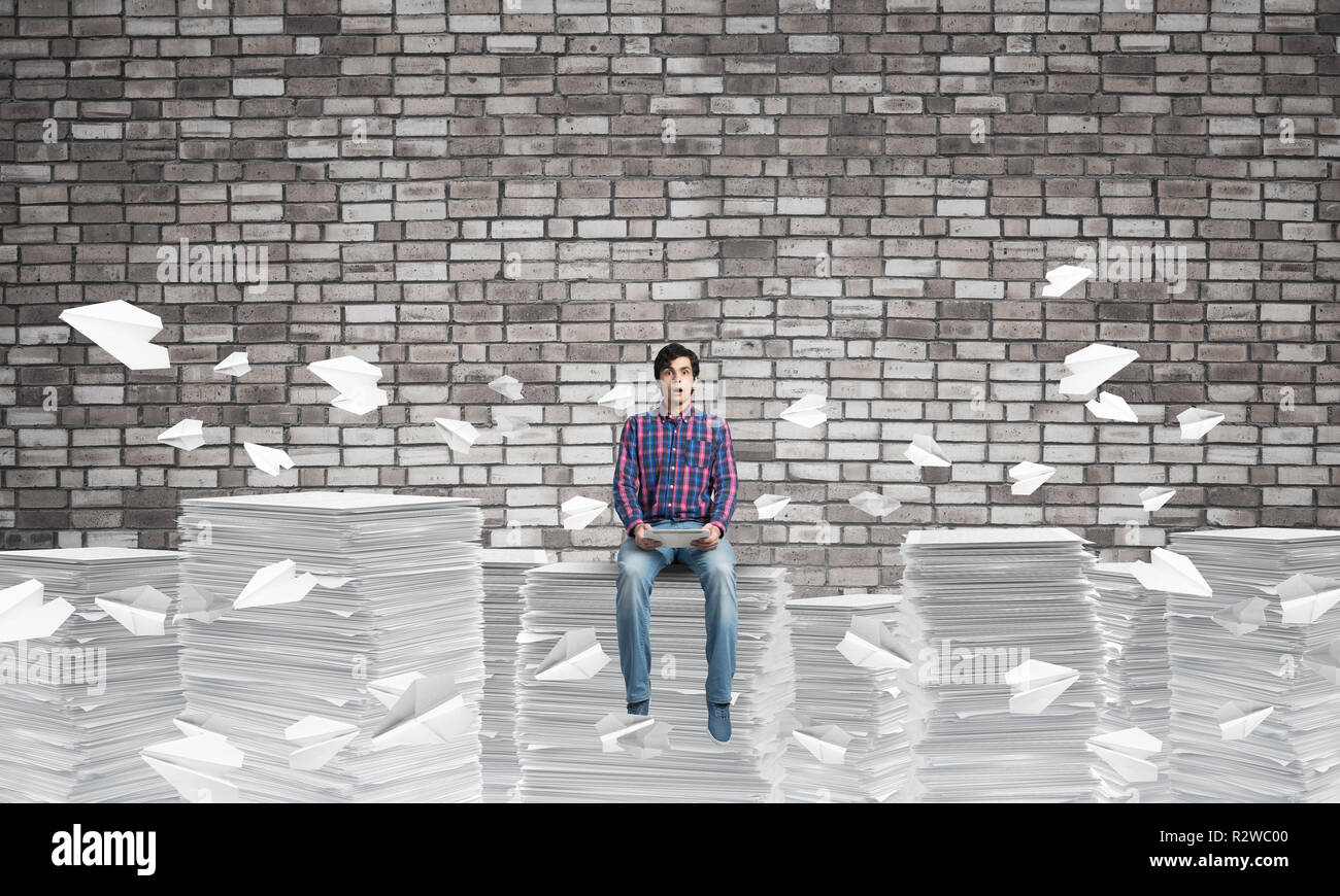 Attractive man sitting on pile of paper documents Stock Photo - Alamy