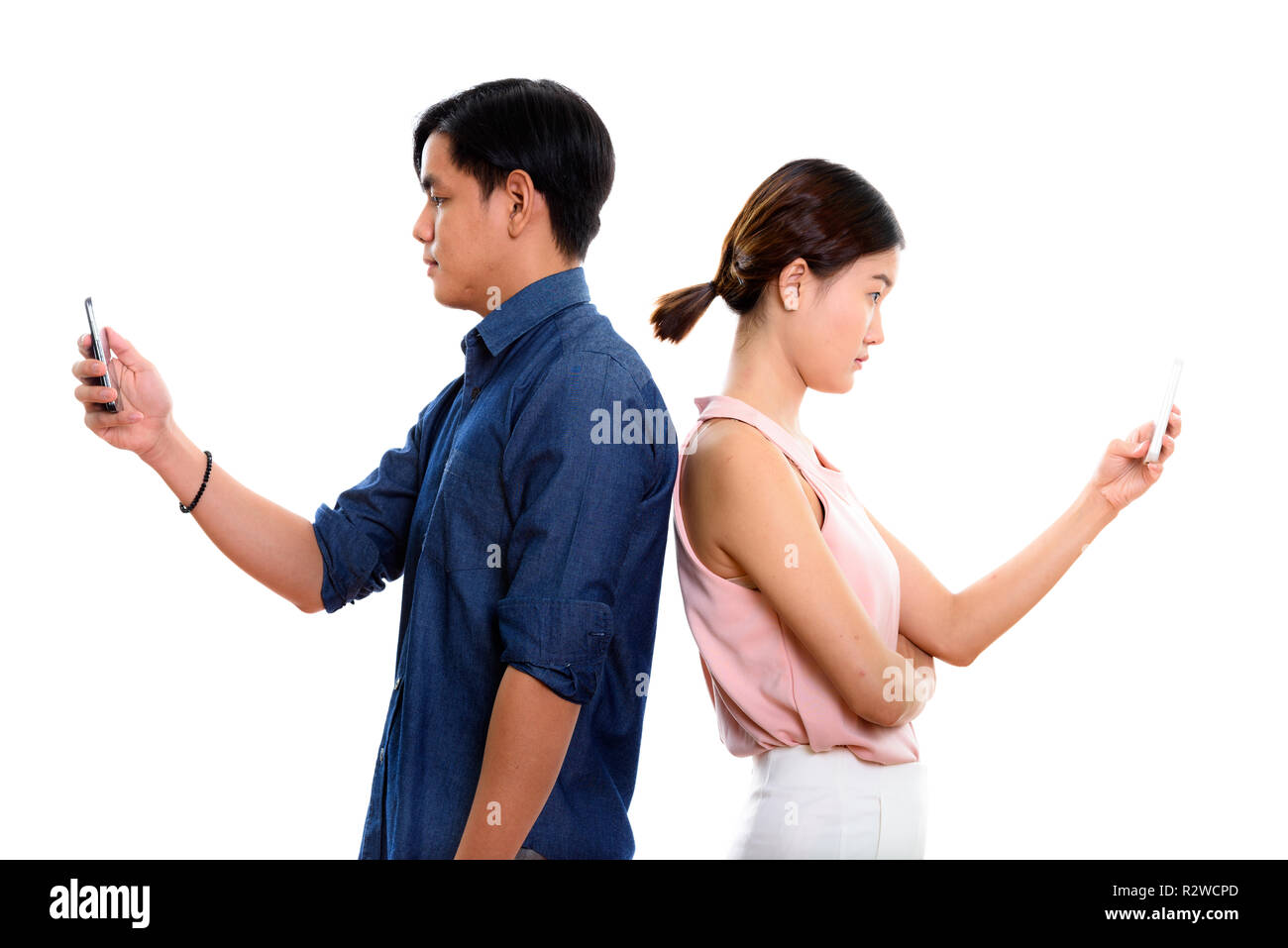 Profile view of young Asian couple using mobile phone together w Stock ...