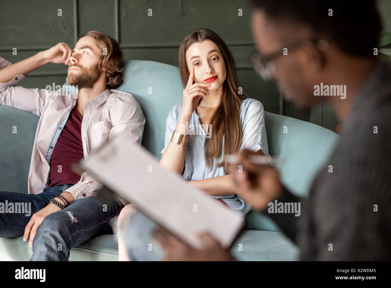 Young serious couple visiting a psychologist sitting on the comfortable ...