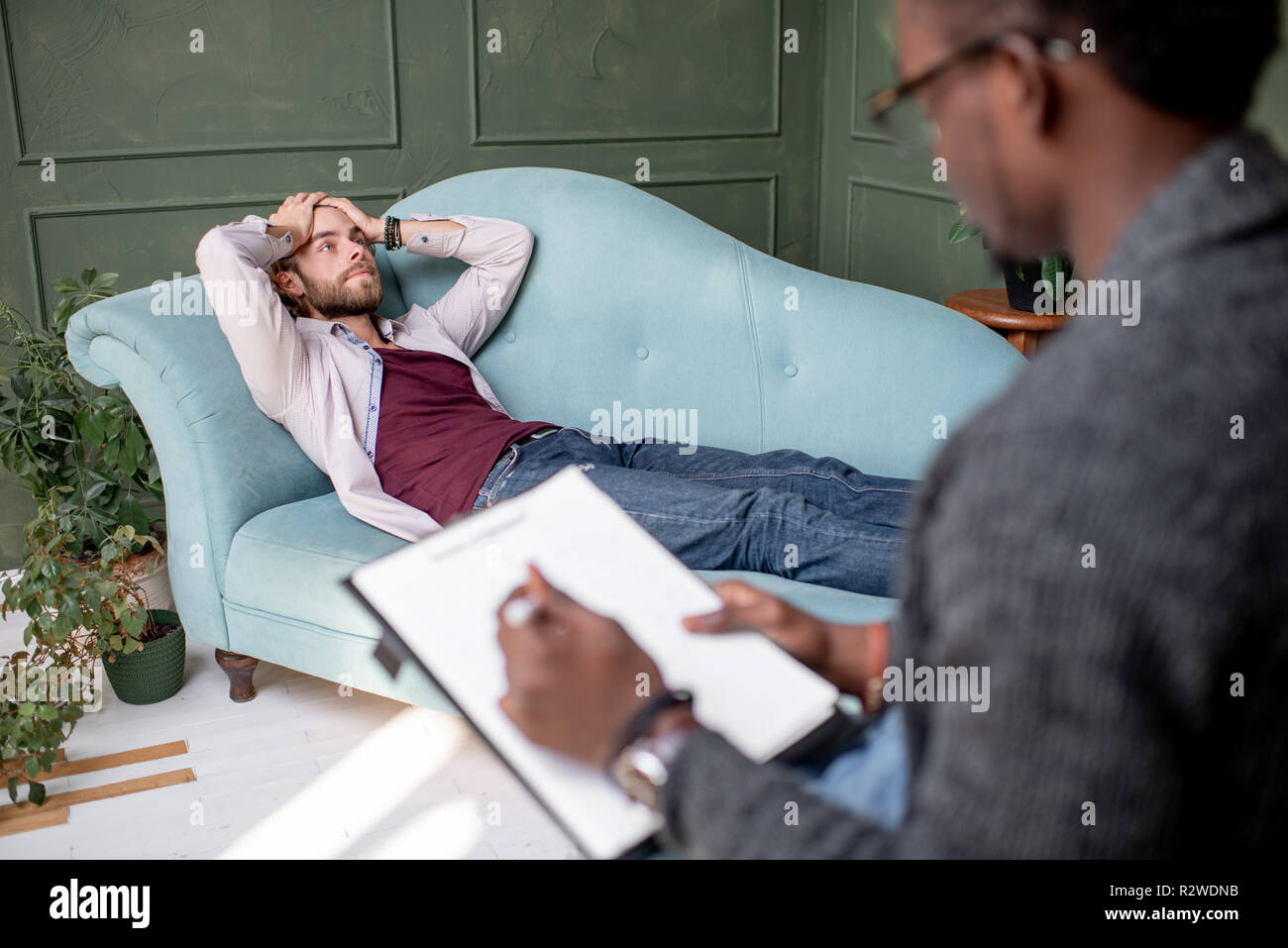 Young caucasian man visiting an african psychologist lying on the ...