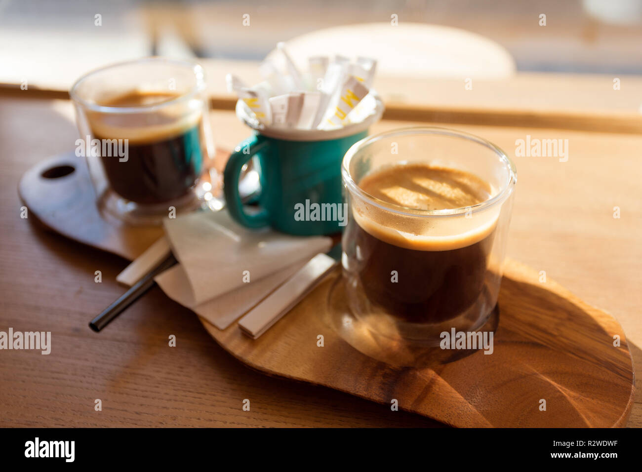 Wooden tray with two cups of coffee on the table in front of the window ...