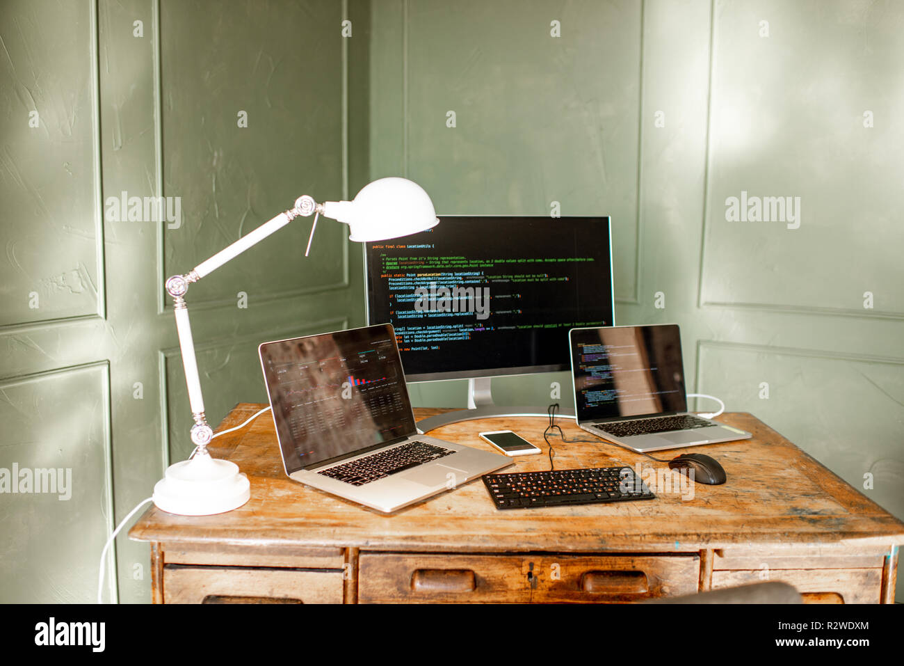 Working place with three computers and programming codes on the screens ...