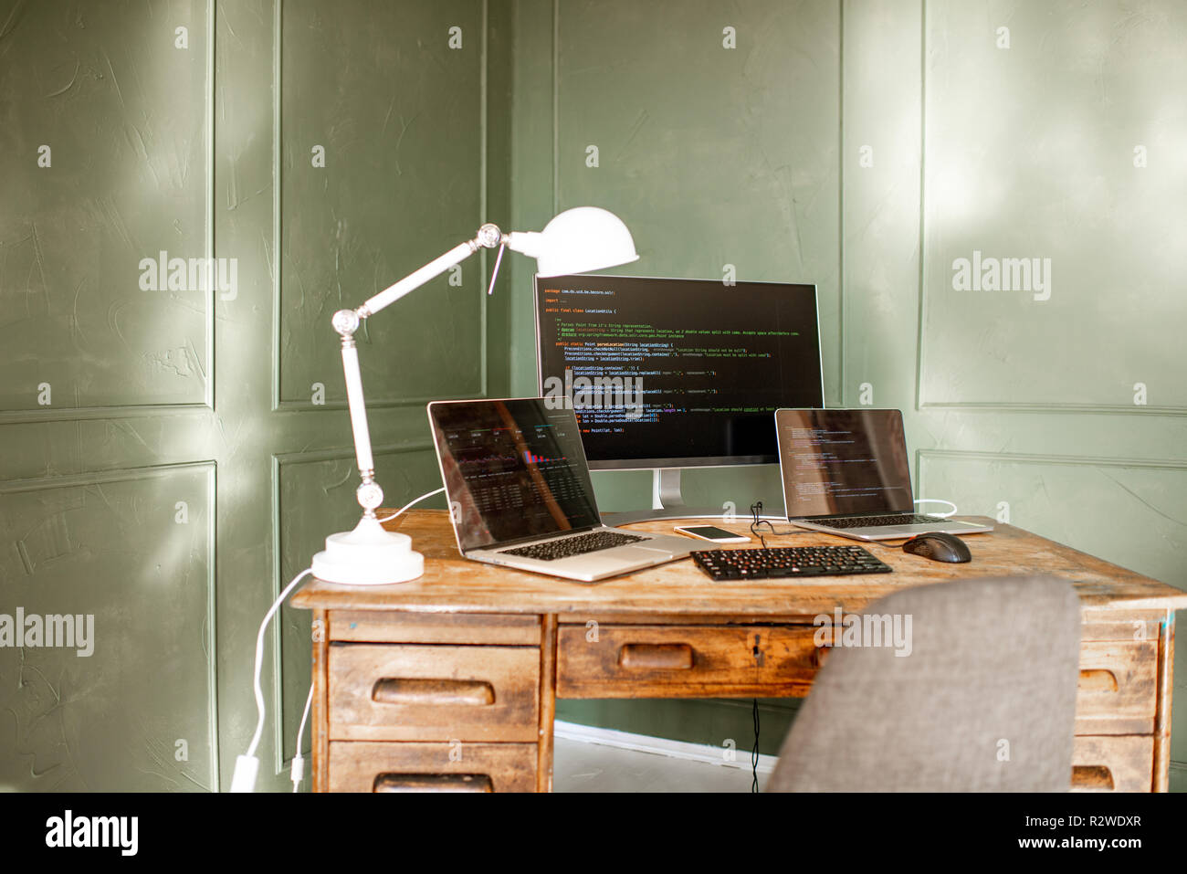 Working place with three computers and programming codes on the screens ...