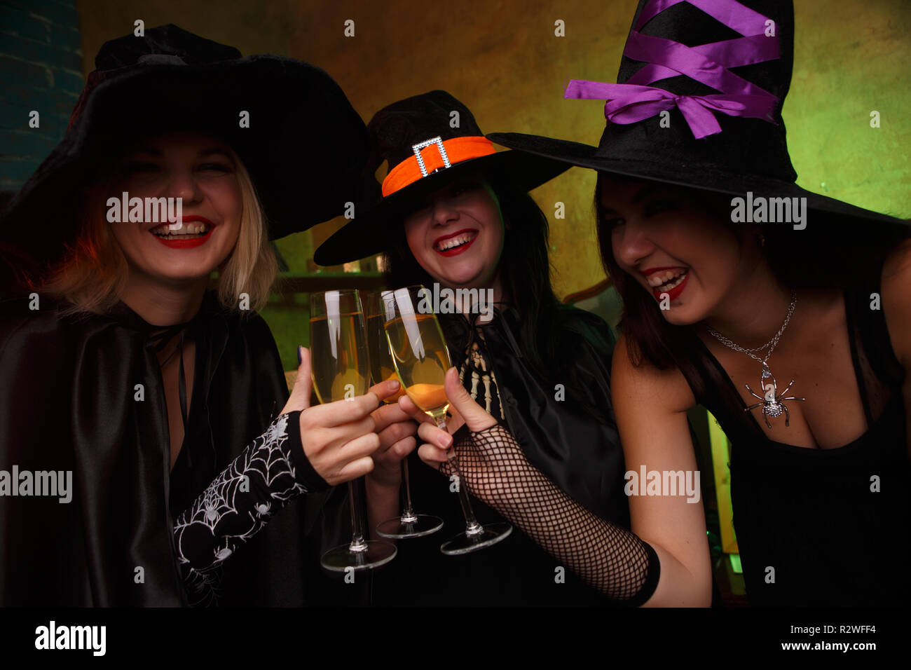 Picture of three happy witches with glass with wine in dark room Stock ...
