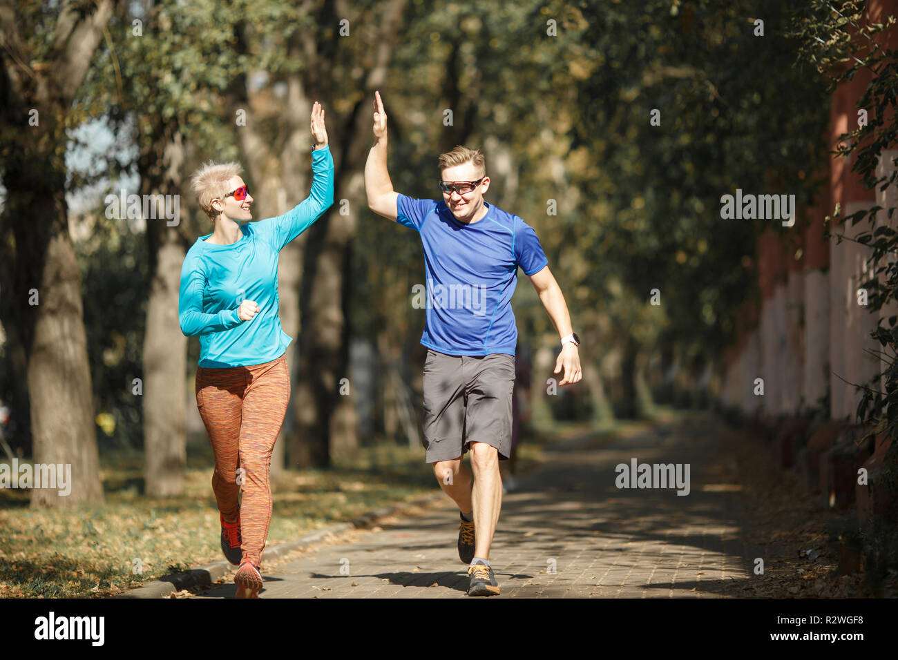 Image of sporting man and woman doing handshake on morning jog in park ...