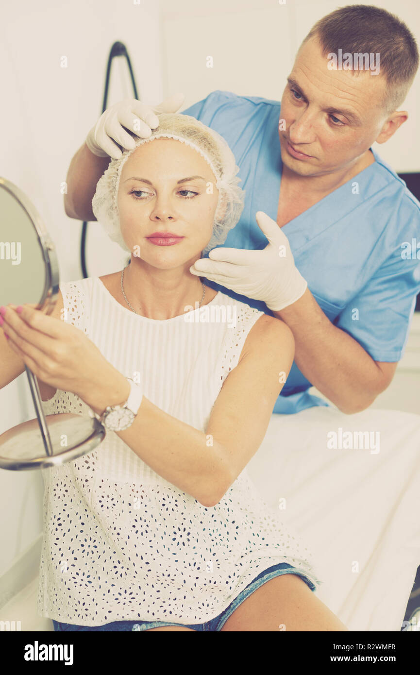 Doctor is examining woman patient behind mirror before the procedure in ...