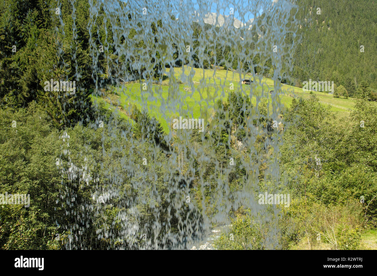Tyrolean Alpine landscape as seen through a curtain of water from ...
