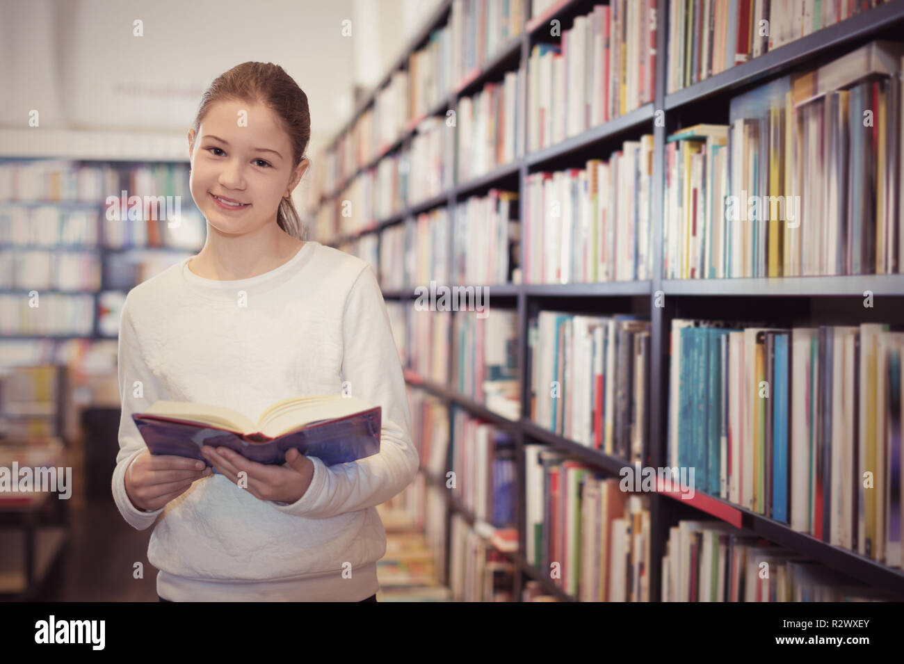 Intelligent cheerful positive smiling preteen girl standing alone near ...