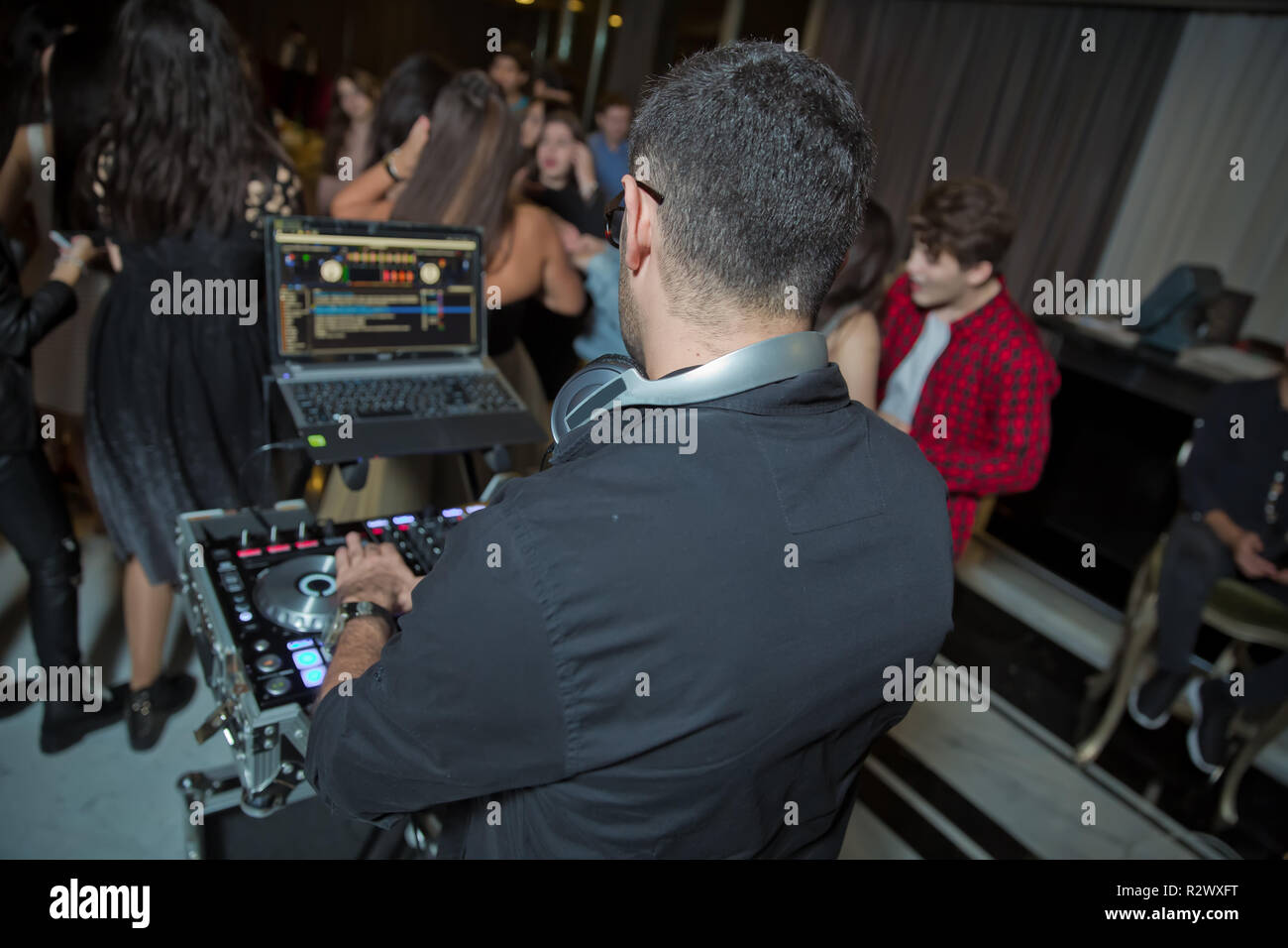DJ with headphones at night club party under the colorful light and ...