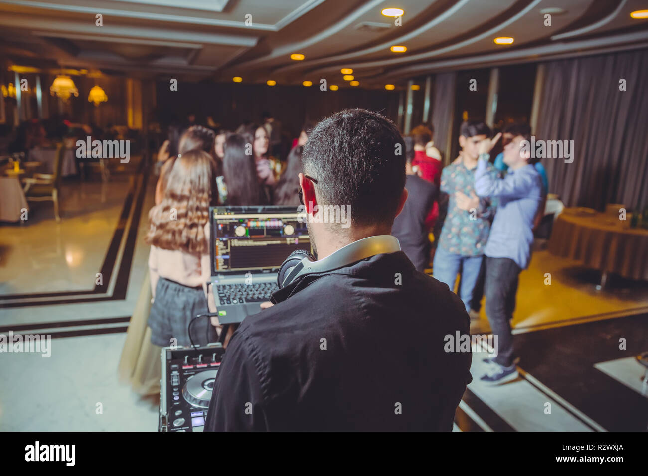 DJ with headphones at night club party under the colorful light and ...