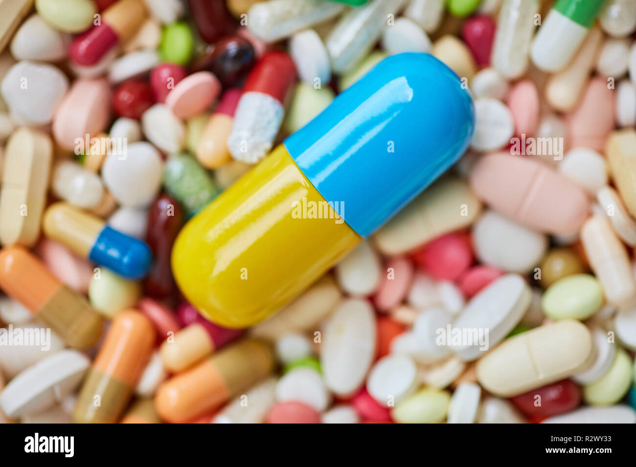 Big pill on a pile of colorful medicines Stock Photo - Alamy