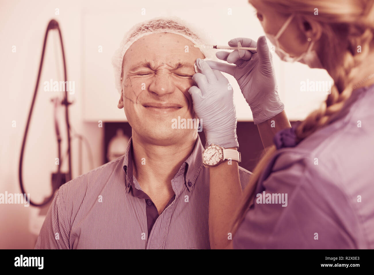 Female doctor is doing injection to patient in skin of face in estetic ...