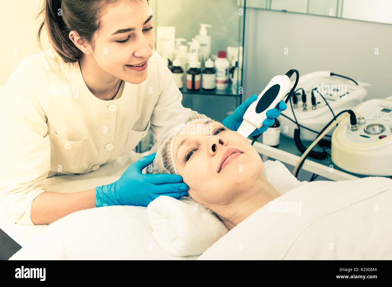 Mature female client undergoing face beauty procedures in center Stock ...