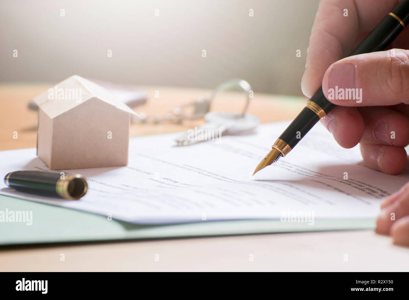 Man hand signing documentation for home mortgage with a pen. Keys and ...