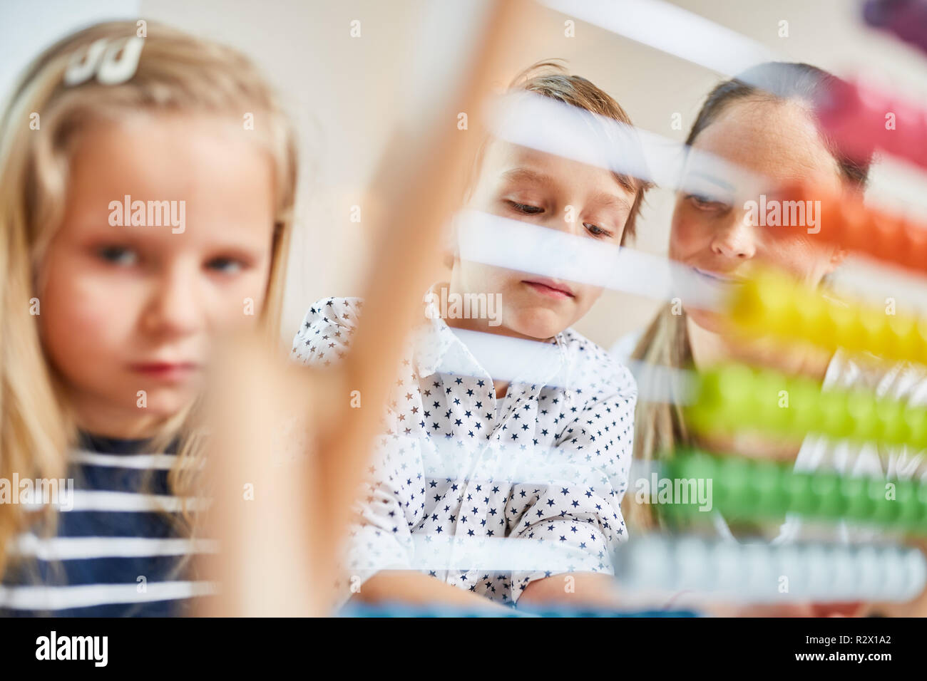 Two children as a student learn arithmetic with the abacus during ...