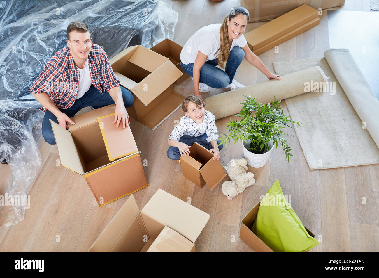 Parents and child moving to a new house as a home with moving boxes ...