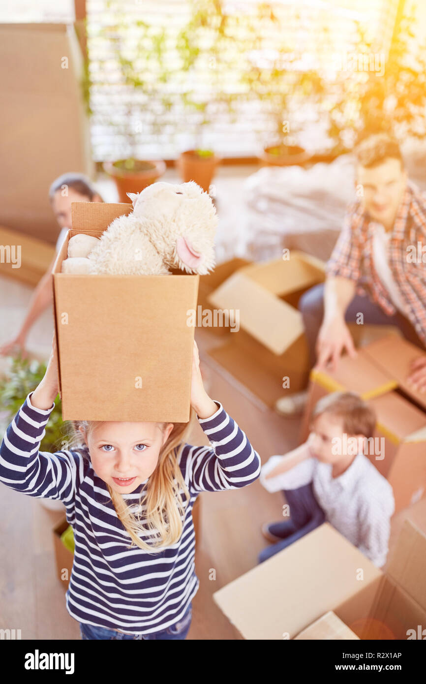 Girl carries moving box with cuddly toys when moving to a family home ...