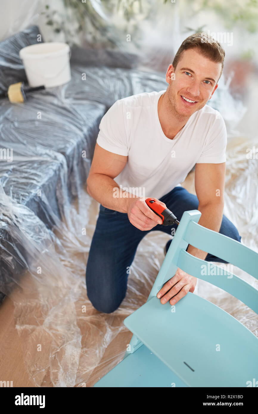 Handyman or craftsman assembles a chair when moving to the new house ...