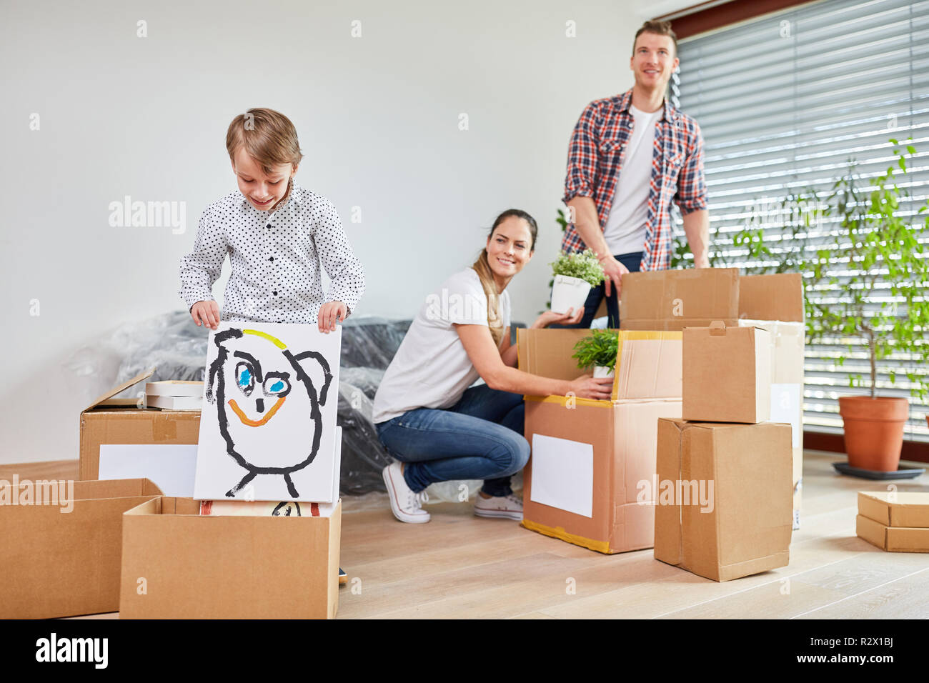 Boy and parents of a family on the move pack together moving boxes ...