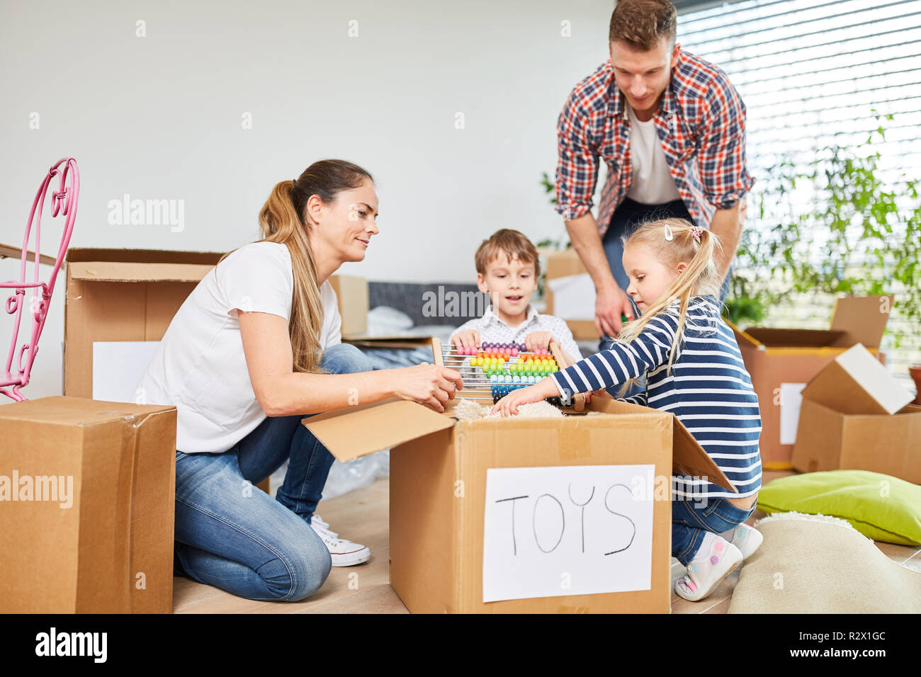 Children and parents in teamwork unpacking moving boxes Stock Photo - Alamy