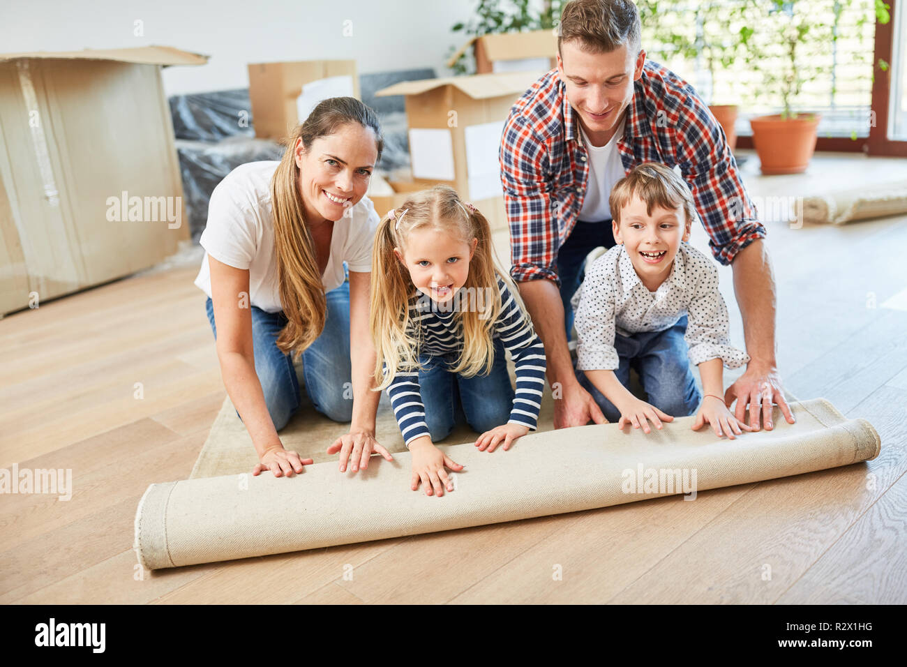 Family and two children moving into their home roll out a carpet Stock ...