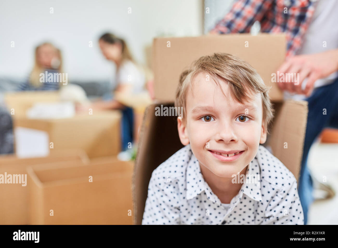 Happy boy moving in or moving to new house plays with moving box Stock ...