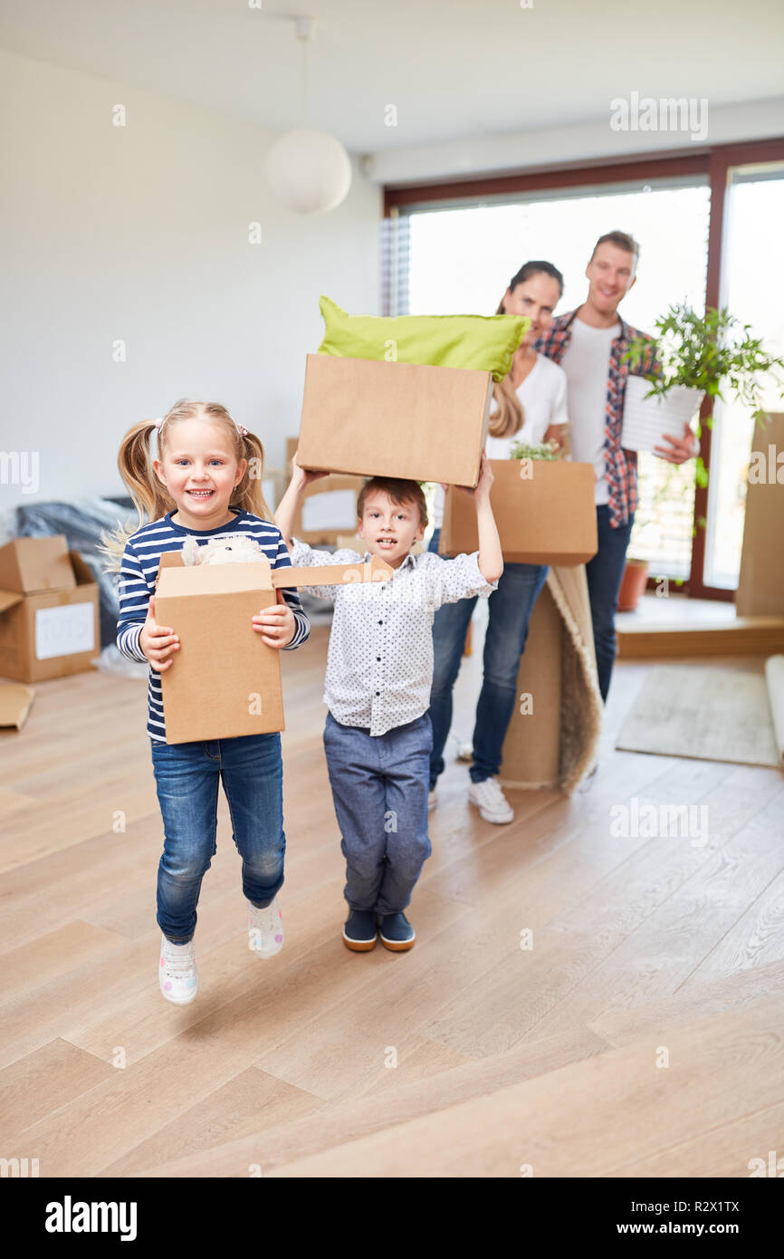 Parents and children enjoy moving and carry moving boxes into the house ...