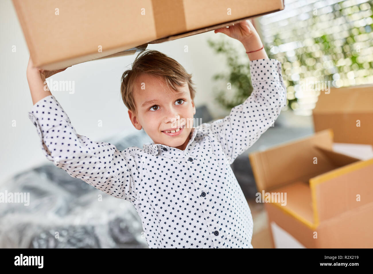 Happy boy carries a moving box when moving in apartment or house Stock ...