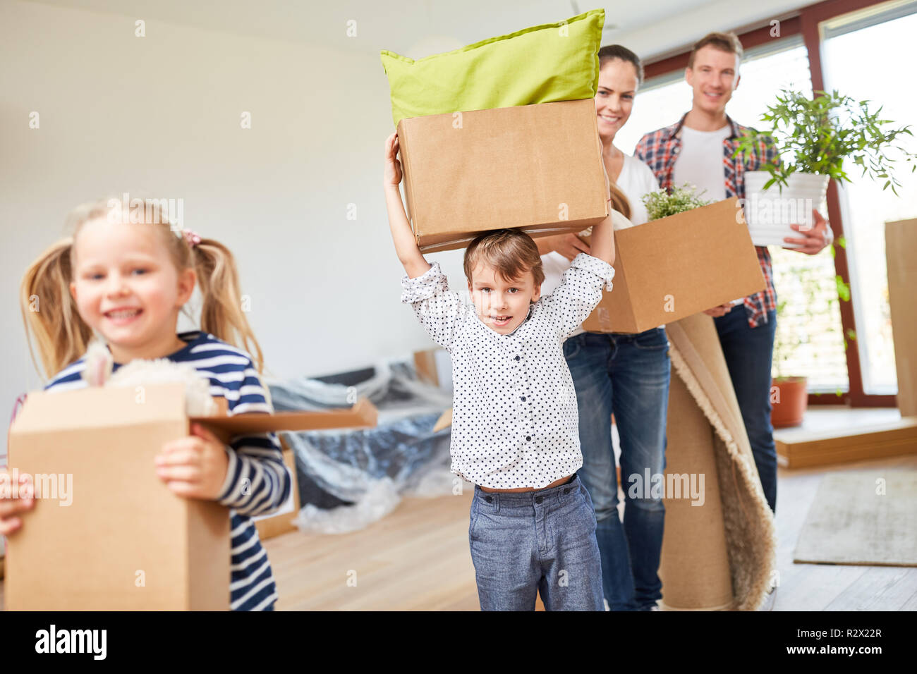 Children enjoy moving and carry boxes with their parents Stock Photo ...