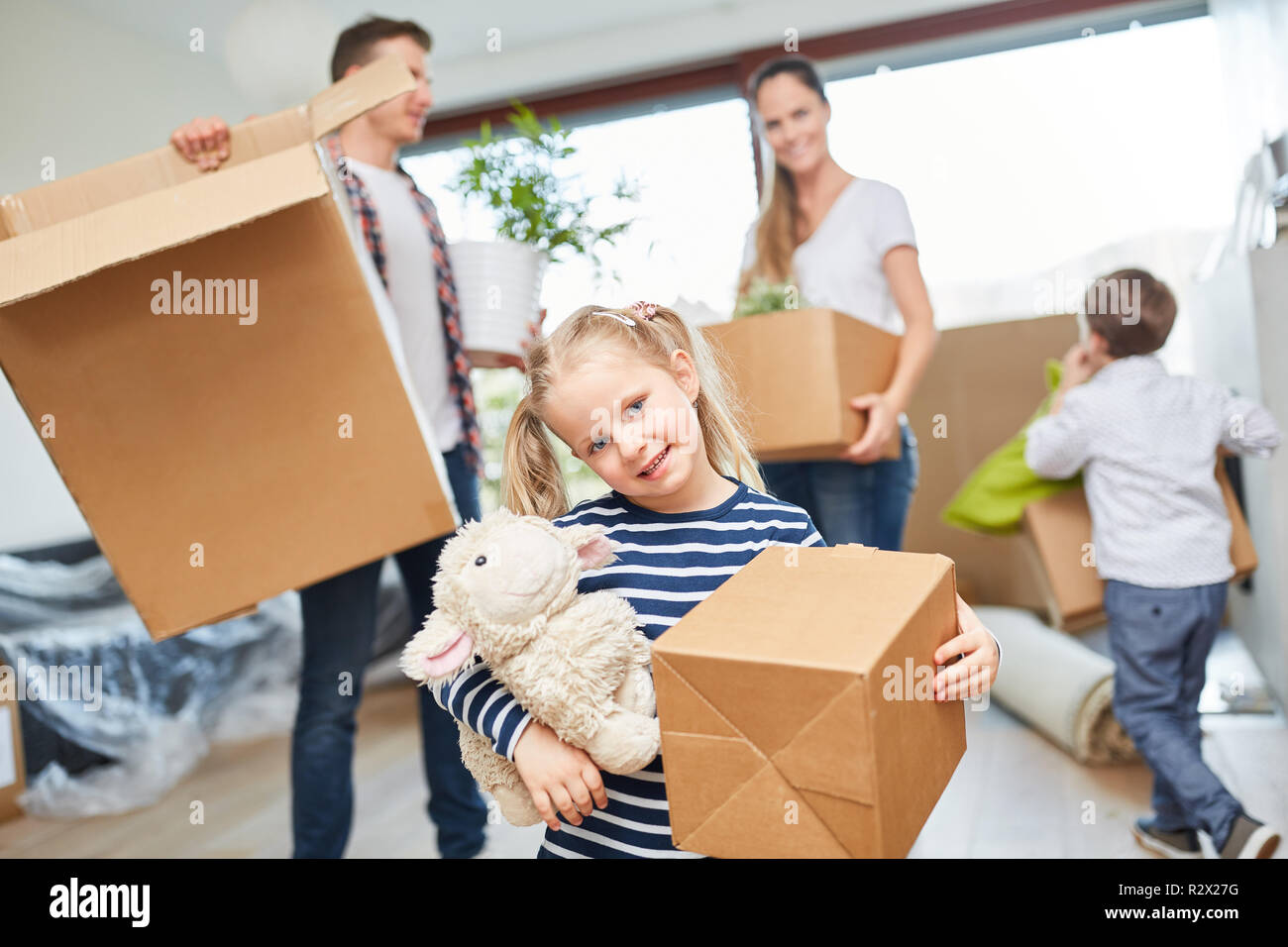 Girl with a cuddly on moving helps to carry moving box Stock Photo - Alamy