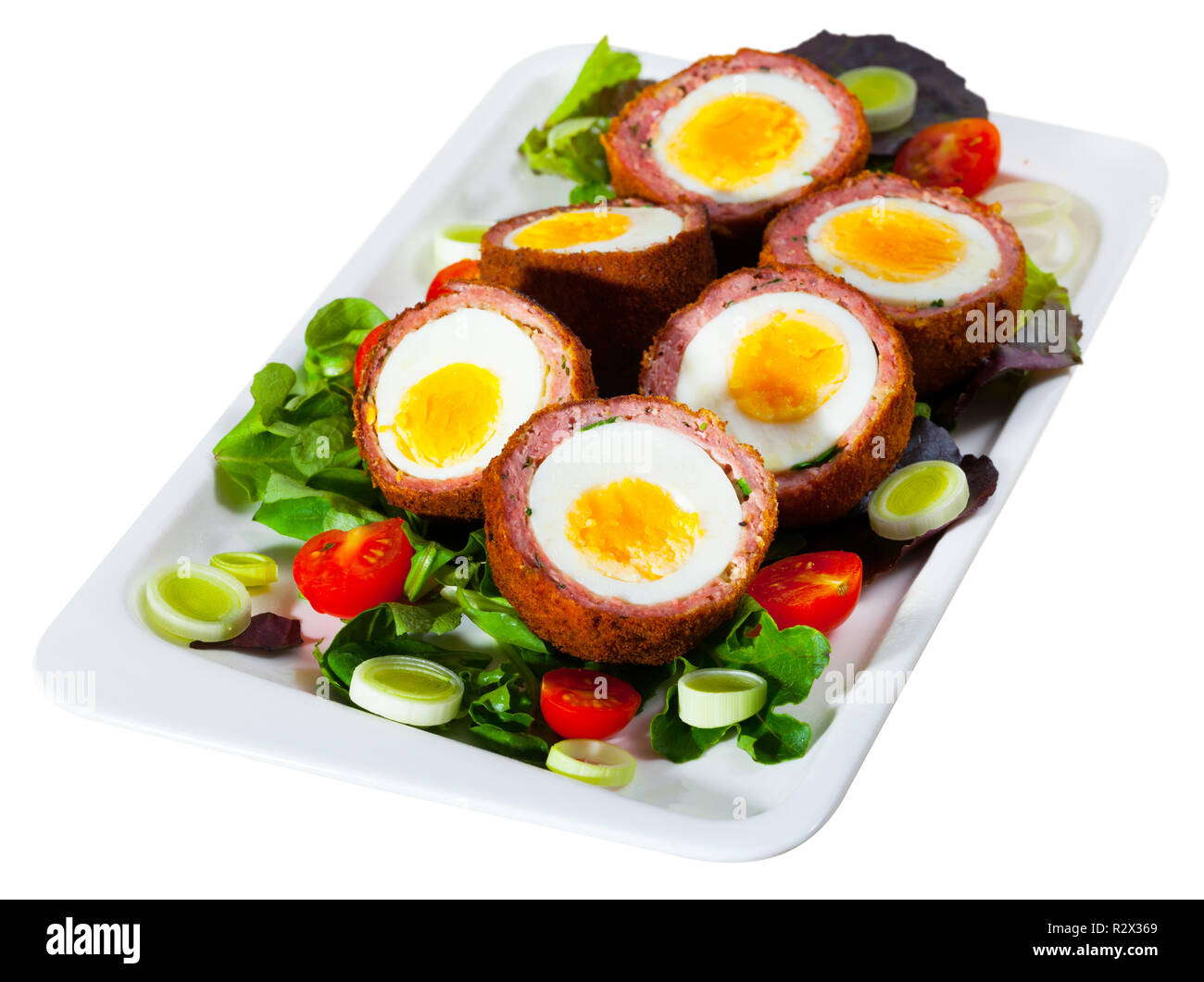 Meat stuffed eggs (Scotch egg) served with cherry tomatoes and greens ...