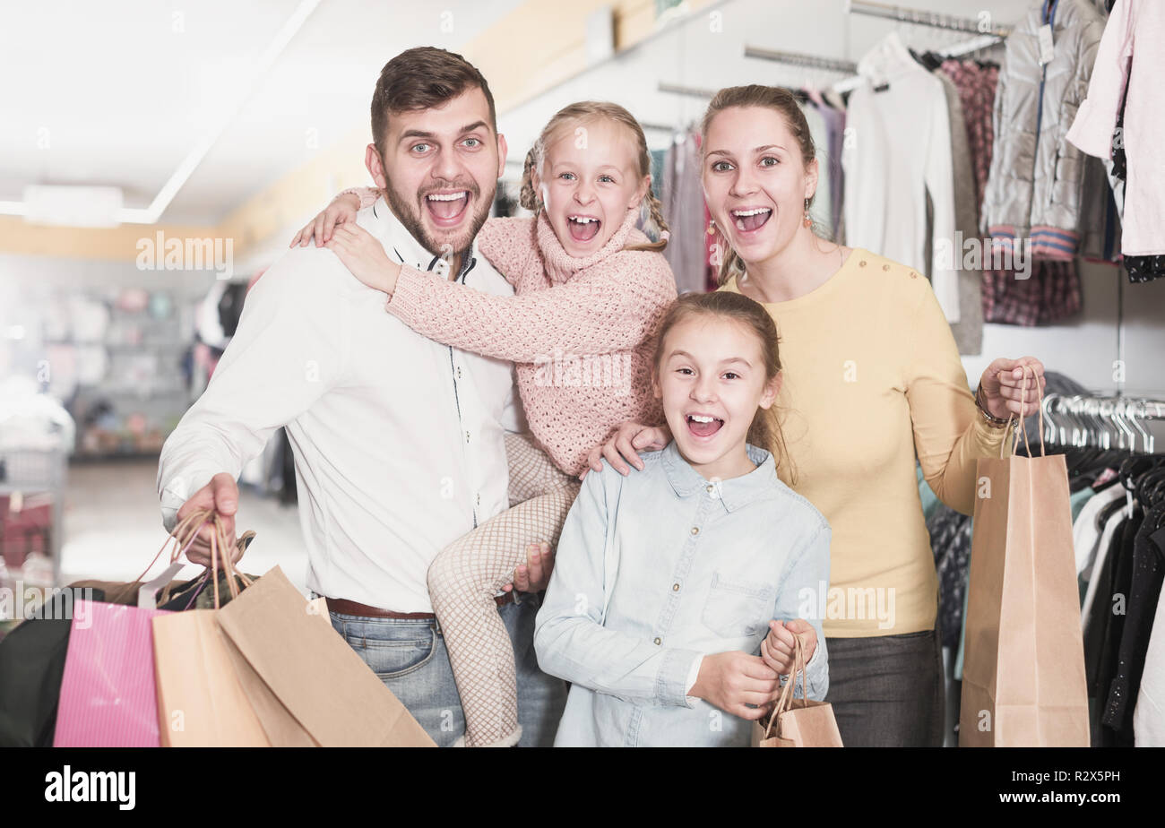 Young smiling family with two daughters holding bags after shopping in ...