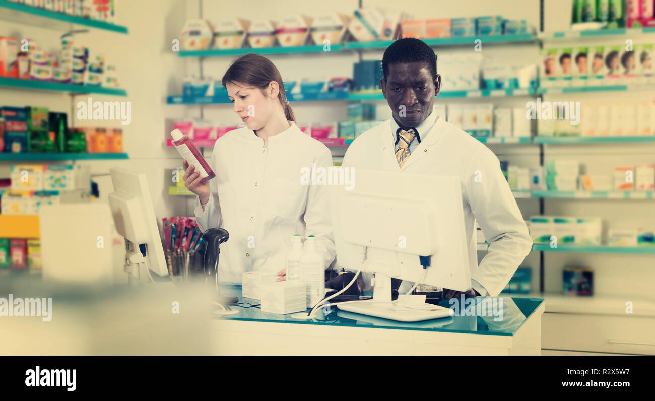 Two professional multinational pharmacists working behind counter in ...
