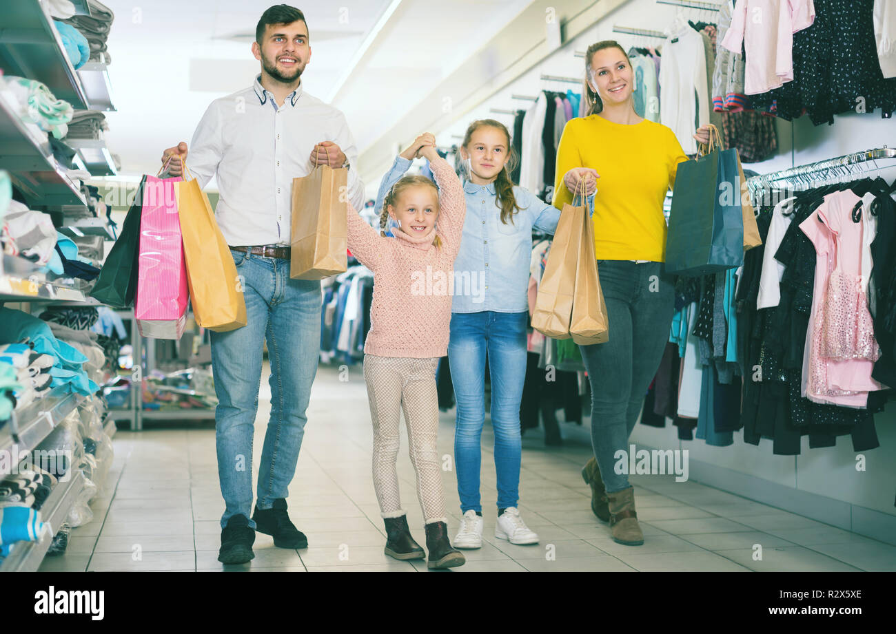 Positive family with two daughters walking in store after shopping ...