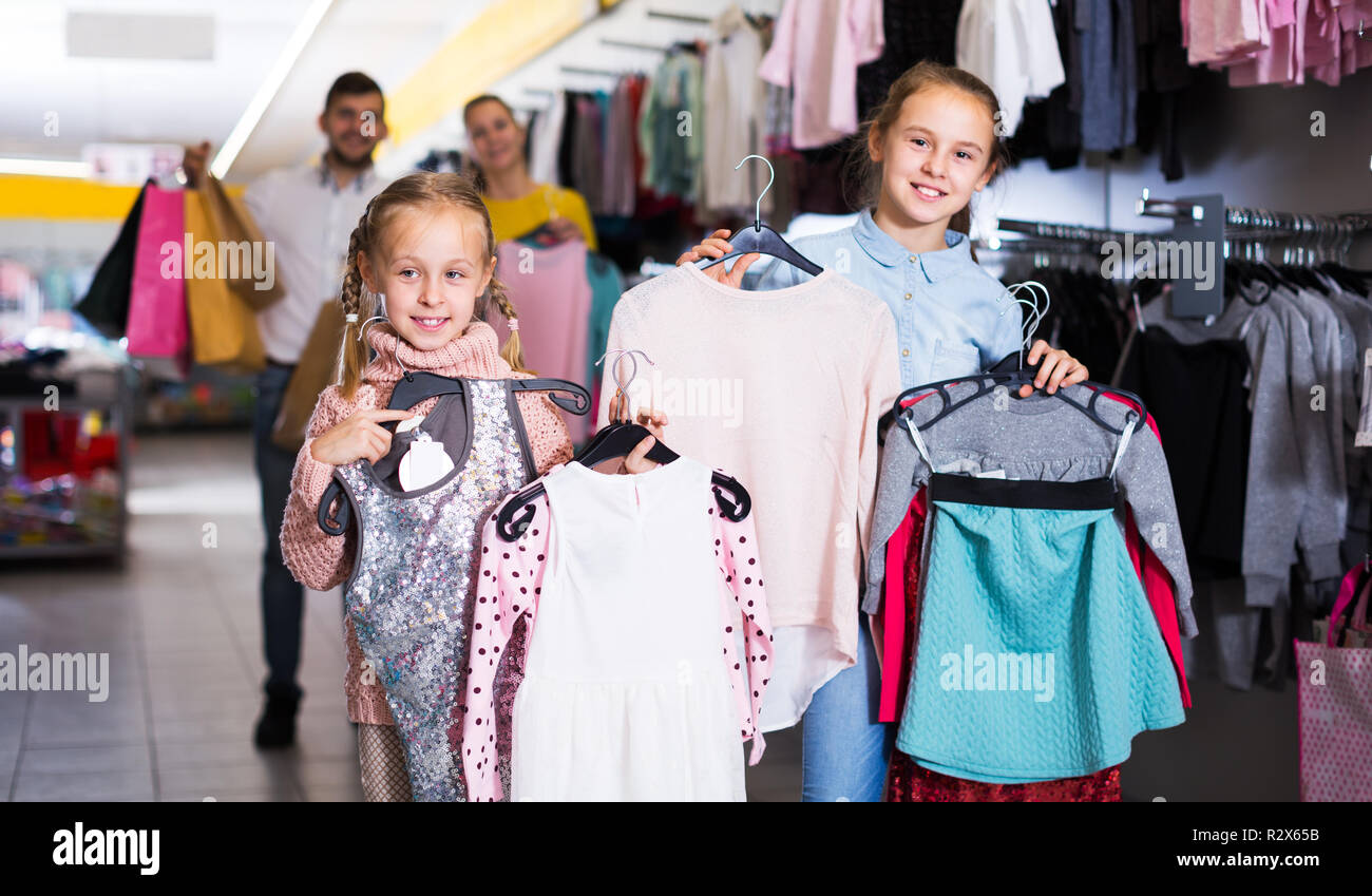 Two cheerful little sisters with mum and dad during family shopping in ...