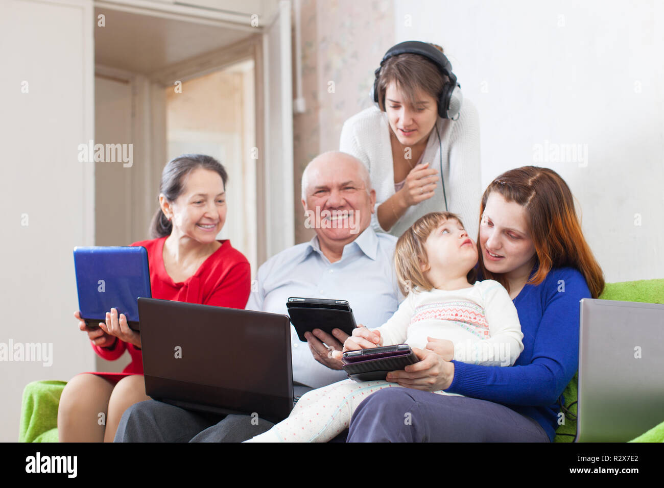 family of with various portable computers on sofa Stock Photo - Alamy