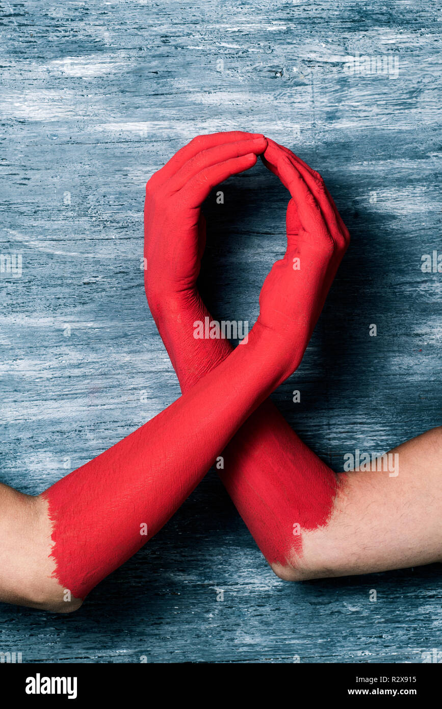 closeup of the arms of two men painted red forming a red awareness ...