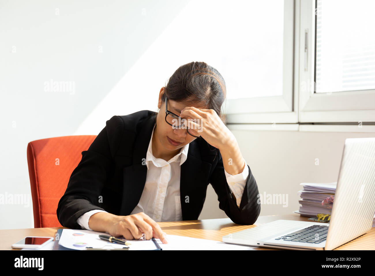 Businesswoman resting hands on head with eyes close at work desk in ...