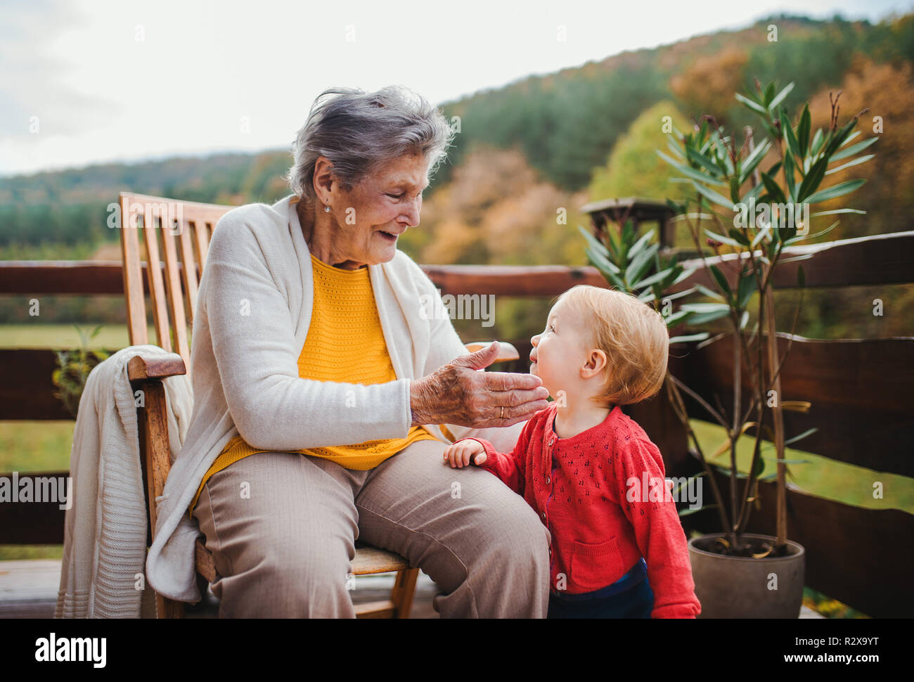 Elderly woman sitting with a toddler great-grandchild on a terrace in ...