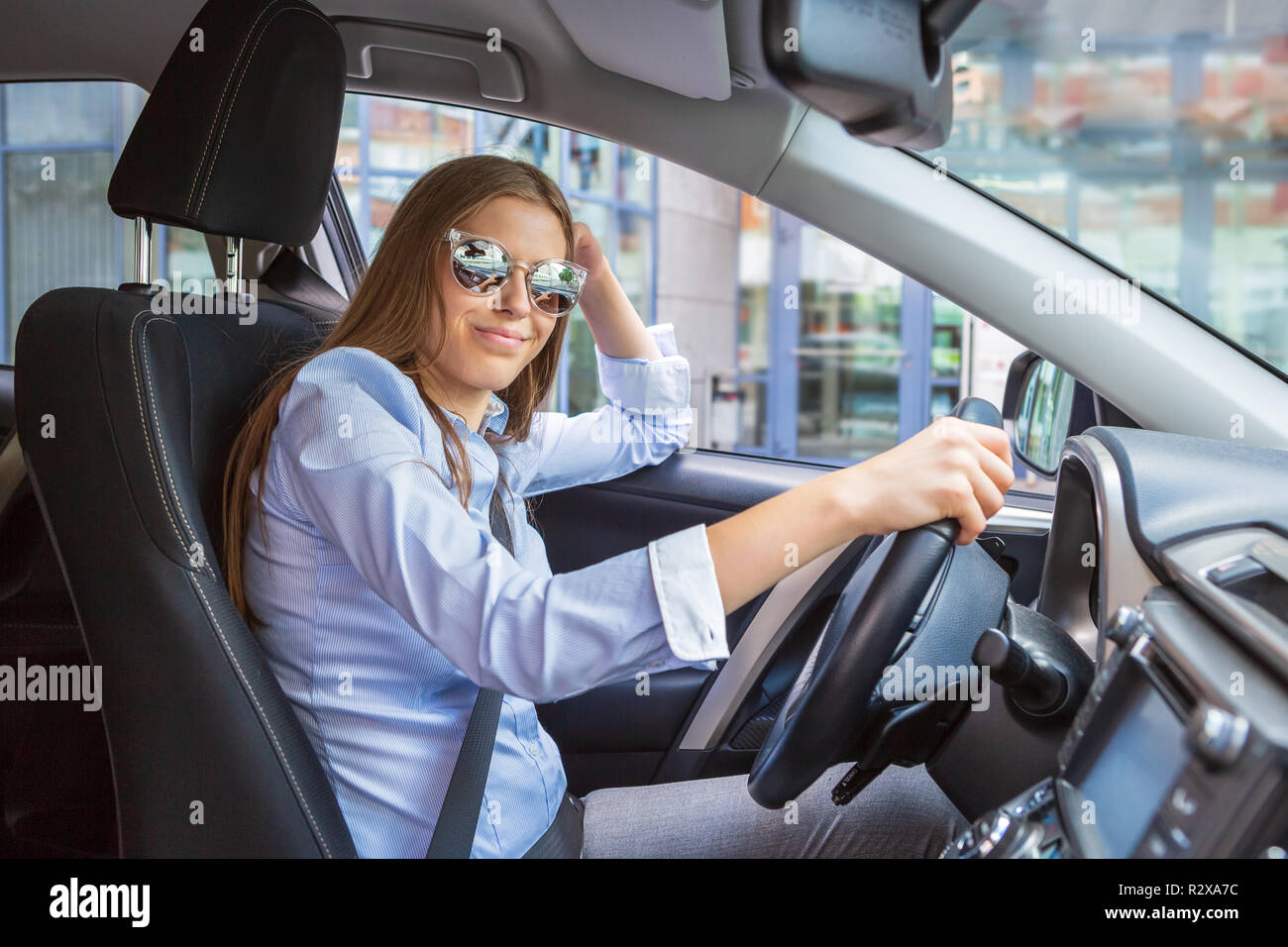 a young girl driving a car in the town Stock Photo - Alamy