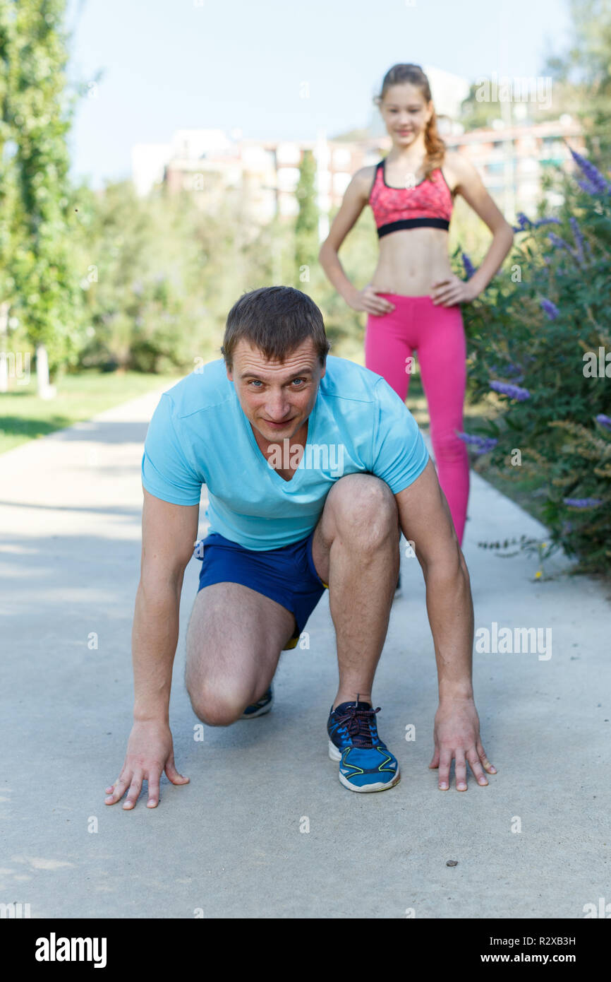 Smiling sporty man standing in start position for run during workout ...