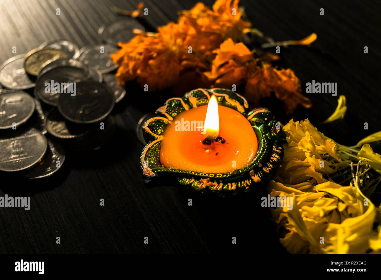 Lit diya placed with flowers and coins to celebrate diwali and ...