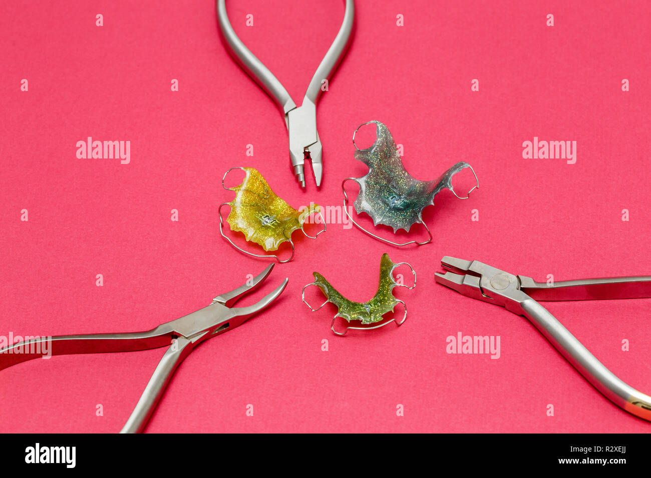 Orthodontic medical metal tools and dental braces or retainers on pink ...