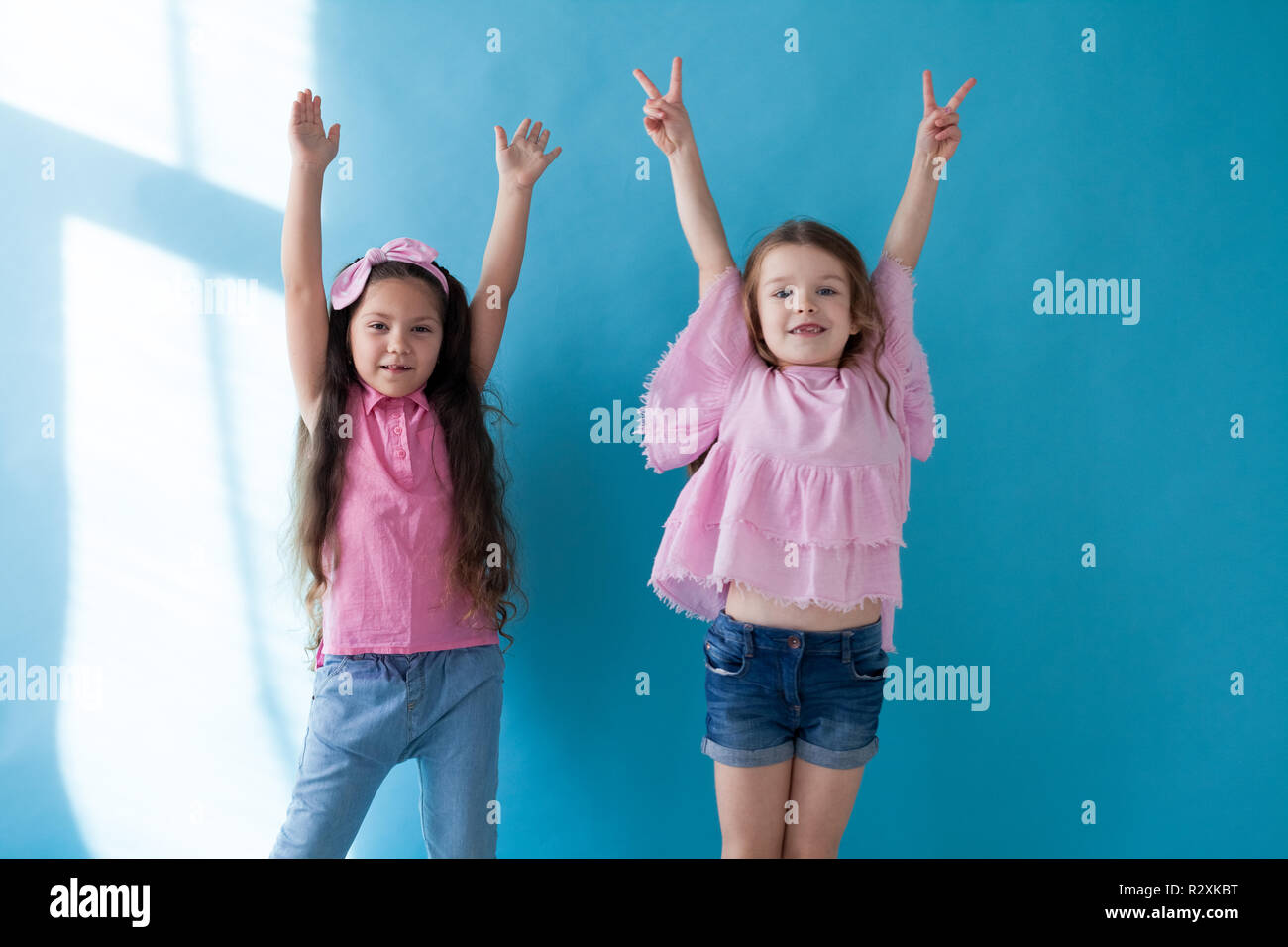 two little girls raise their hands up Stock Photo - Alamy