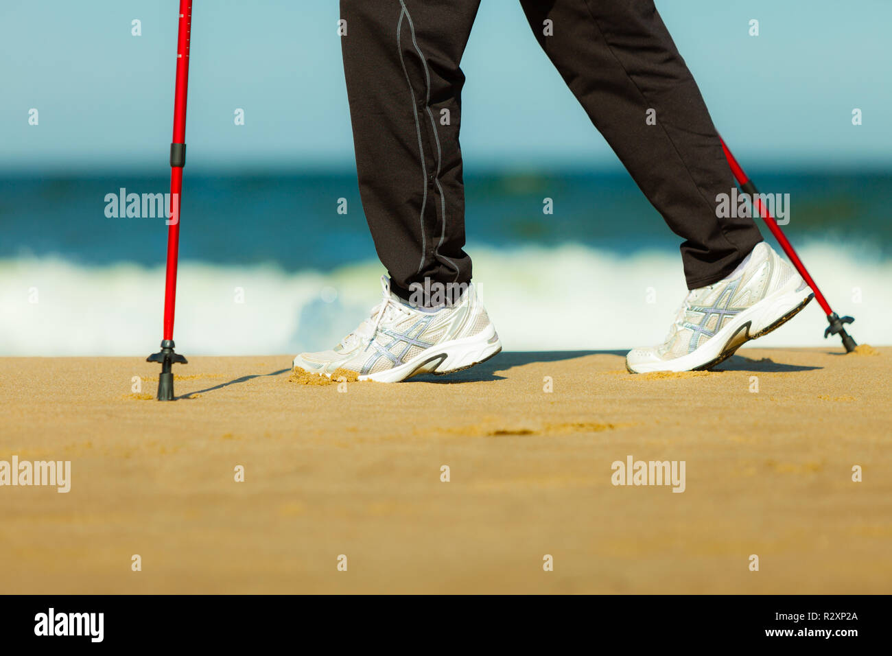Nordic walking. Closeup of female legs hiking on the beach. Active and ...